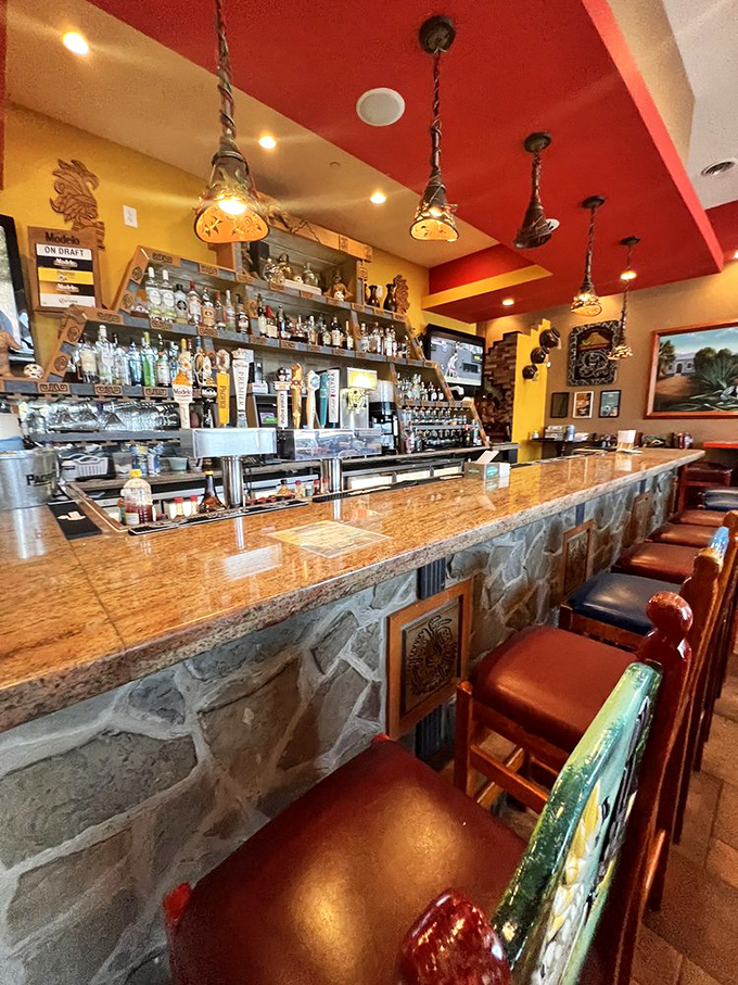 The bar isn't just serving drinks—it's dispensing liquid sunshine in margarita form beneath a ceiling that mimics a Mexican sunset.