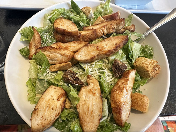 Caesar salad elevated beyond the ordinary—crisp romaine embraced by creamy dressing, crowned with perfectly seasoned chicken that means business.
