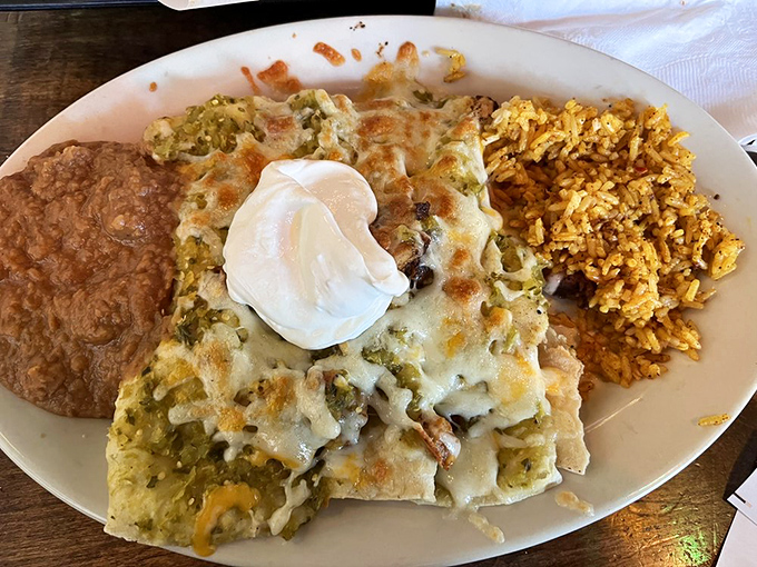 A plate that whispers "comfort" but shouts "flavor" – where melted cheese blankets perfectly stuffed enchiladas alongside festive Mexican rice.