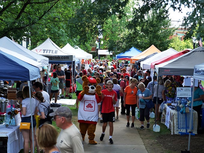 The farmers market brings together vendors, visitors, and apparently mascots—because nothing says "fresh produce" like a person in a bear costume on a hot summer day.