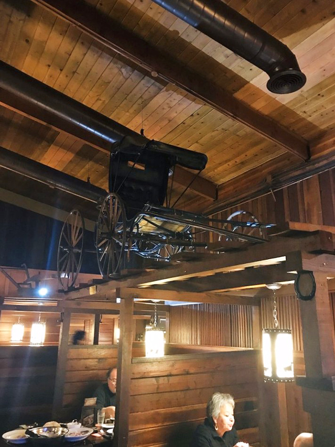 An antique carriage suspended from wooden beams—because nothing says "serious about meat" like decorating with transportation from the 1800s.