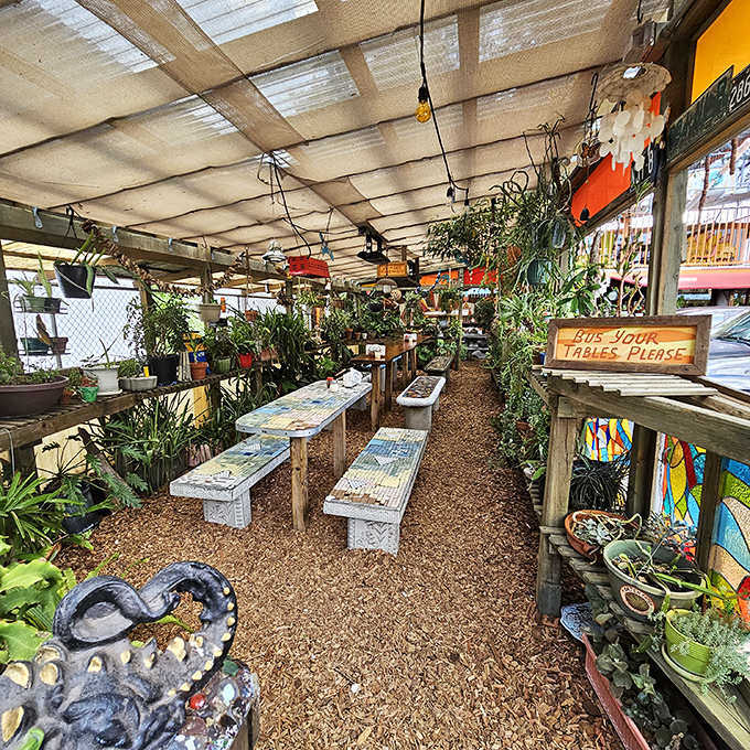 Garden seating that feels like dining in a bohemian greenhouse – mosaic tables nestled among plants create a secret hideaway for pizza enjoyment.