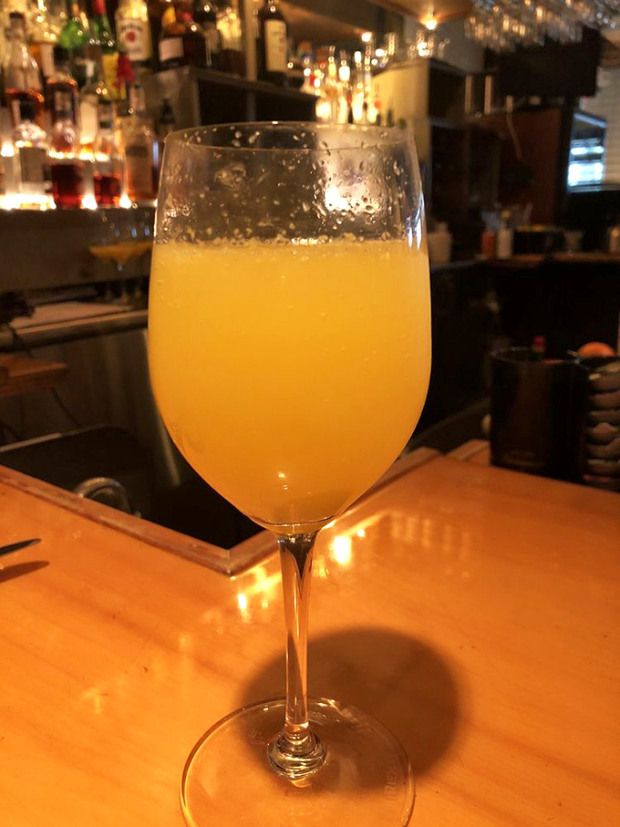 A mimosa that captures sunshine in a glass, proving that sometimes the simplest pleasures—bubbles and juice—create the most perfect moments.