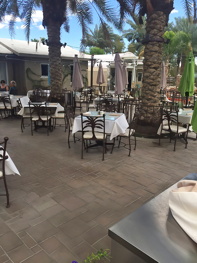 Al fresco dining surrounded by towering palms creates a peaceful oasis. White tablecloths add a touch of elegance to this desert dining experience.