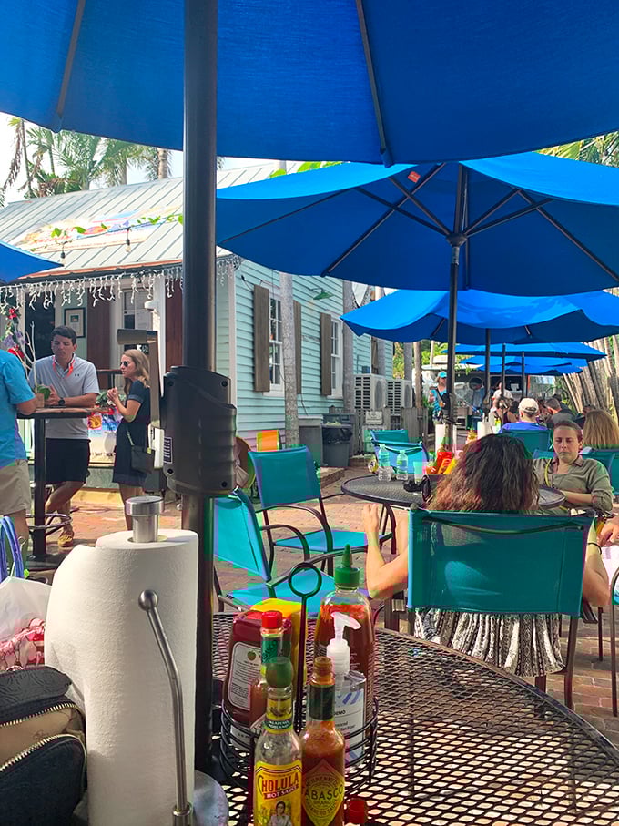 The quintessential Keys dining experience: blue umbrellas, hot sauce on every table, and conversations floating on the salt-tinged breeze.