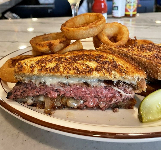 The patty melt—that glorious marriage of beef, cheese, and grilled bread. Those onion rings are the bridesmaids stealing the show.