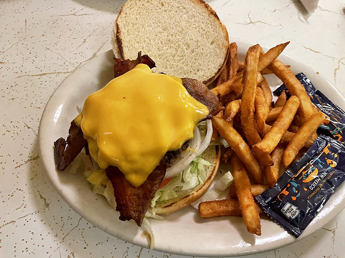This isn't just a burger – it's a hand-formed testament to simplicity, with melted American cheese cascading down the sides like a yellow waterfall.