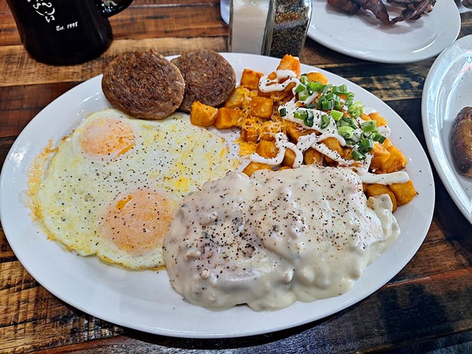 Two sunny-side up eggs flanking sausage patties with a side of sweet potato hash—a breakfast plate that demands to be photographed.