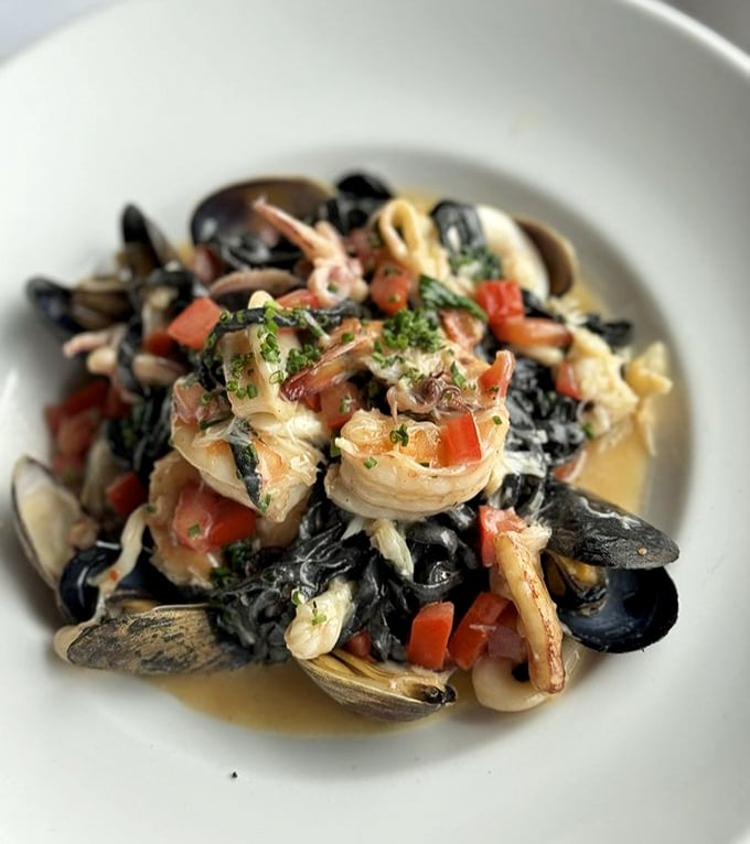 Black pasta that looks like midnight and tastes like morning at the fish market – fresh seafood nestled in squid ink perfection.