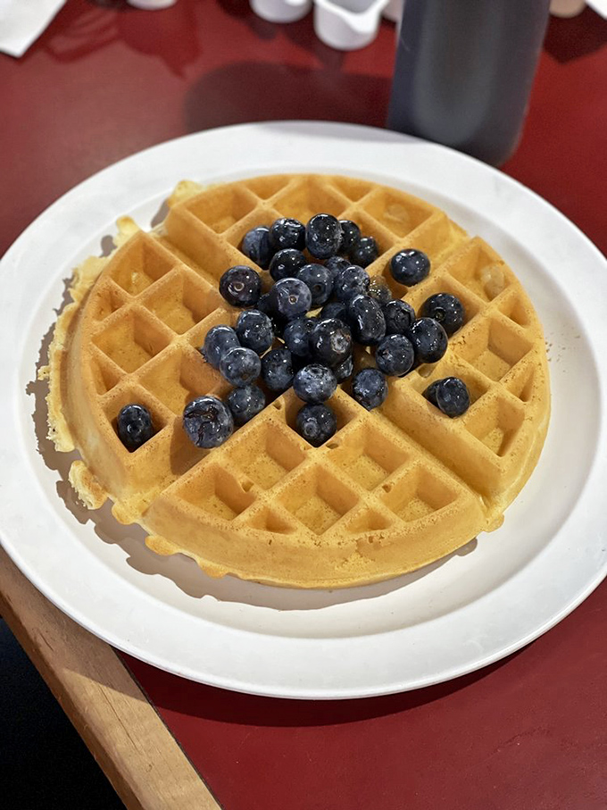 A golden waffle crowned with fresh blueberries—nature's candy—creating the perfect balance between virtuous and indulgent breakfast choices.