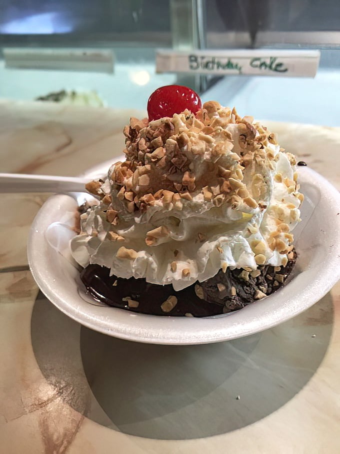 A mountain of whipped cream and nuts crowns this brownie sundae—dessert architecture that deserves its own blueprint.