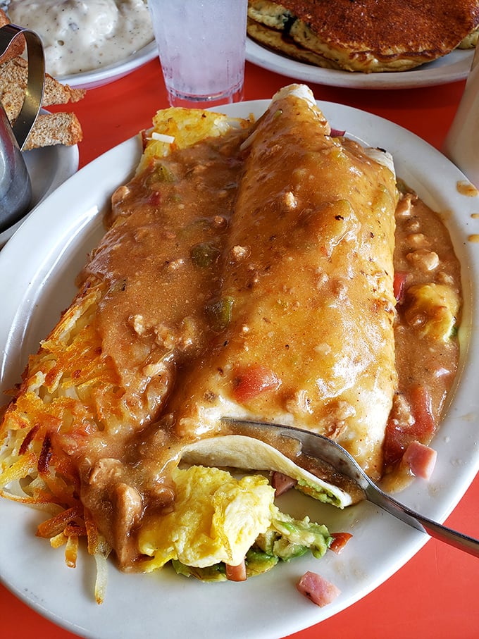 This burrito isn't just food, it's architecture – a structural marvel of eggs, cheese, and perfectly spiced meat under a blanket of sauce.