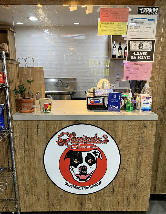 The counter tells the story—a smiling dog logo, cash-is-king sign, and plants that somehow survive in a sandwich shop. Character in every detail.