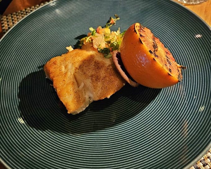 A perfectly cooked piece of fish alongside a charred citrus half—simple, elegant, and proof that sometimes less truly is more.