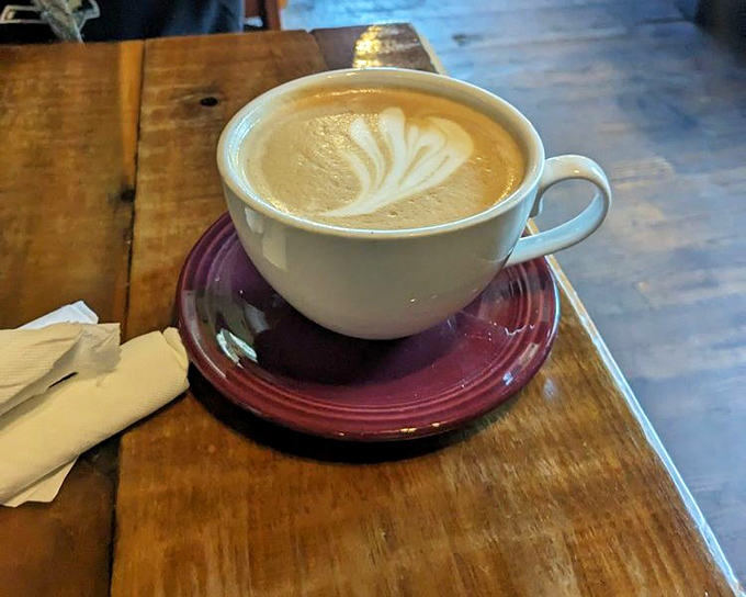 This isn't just coffee—it's a cinnamon bun latte artwork, where barista skill meets comfort-in-a-cup on a rustic wooden table.