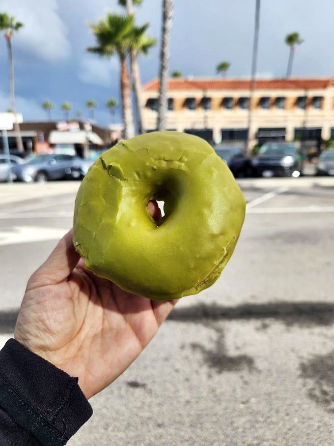 The matcha donut against Newport Beach's palm trees creates a perfect California moment—where wellness culture and indulgence somehow peacefully coexist.