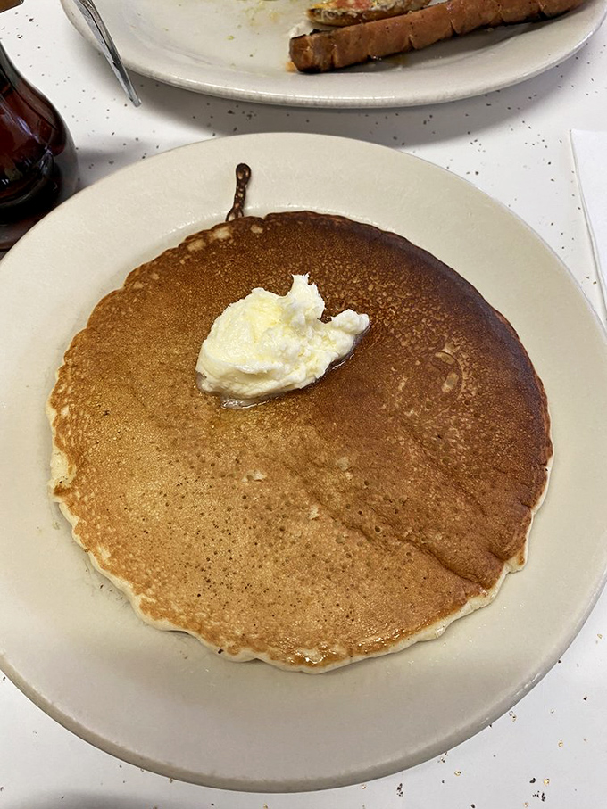 Pancake artistry in its purest form. That perfect golden-brown canvas awaits only your choice of syrup trajectory – straight down the middle or spiral approach?