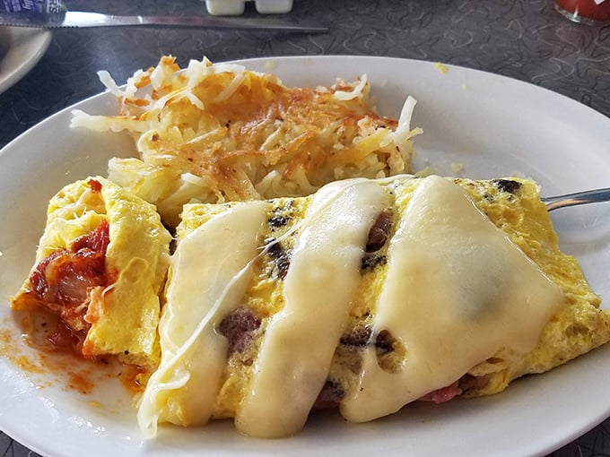 This isn't just an omelet – it's a masterpiece of folded eggs cradling pastrami and melted cheese with hash browns standing guard on the side.
