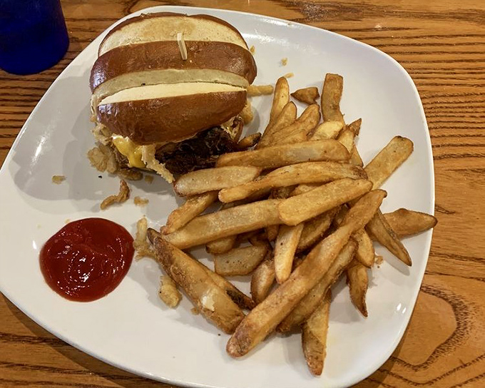 A sandwich that requires both hands and your full attention—the pulled pork nestled in that pretzel bun isn't just food, it's an event.