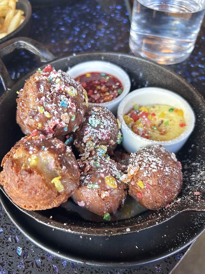 Not your average donut holes—these colorful, sugar-dusted spheres are served with dipping sauces that transform breakfast into a joyful, interactive experience.