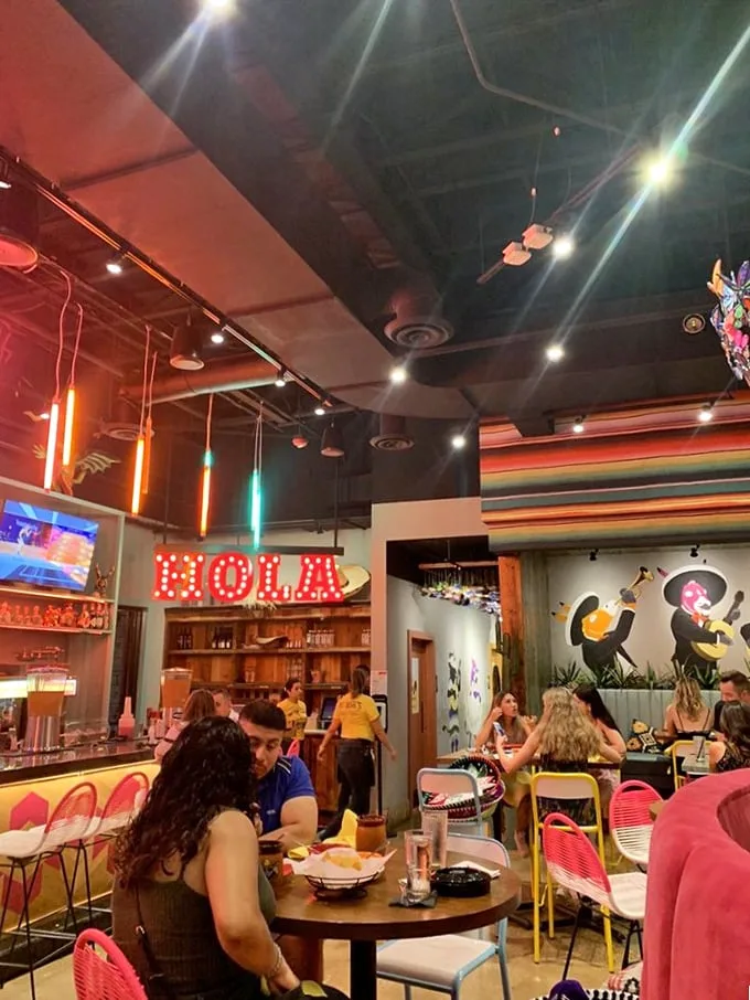 The "HOLA" sign isn't just decor—it's a promise of the hospitality that awaits. Colorful lighting sets the perfect mood.