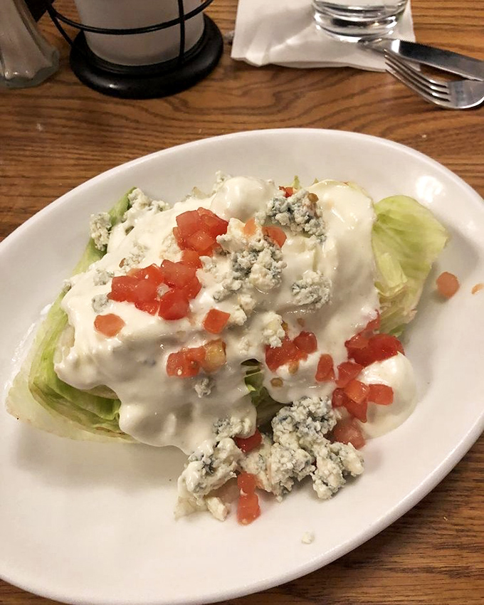 The wedge salad—that retro steakhouse classic that proves sometimes the simplest combinations (crisp lettuce, creamy dressing, blue cheese, tomato) create the most satisfying bites.