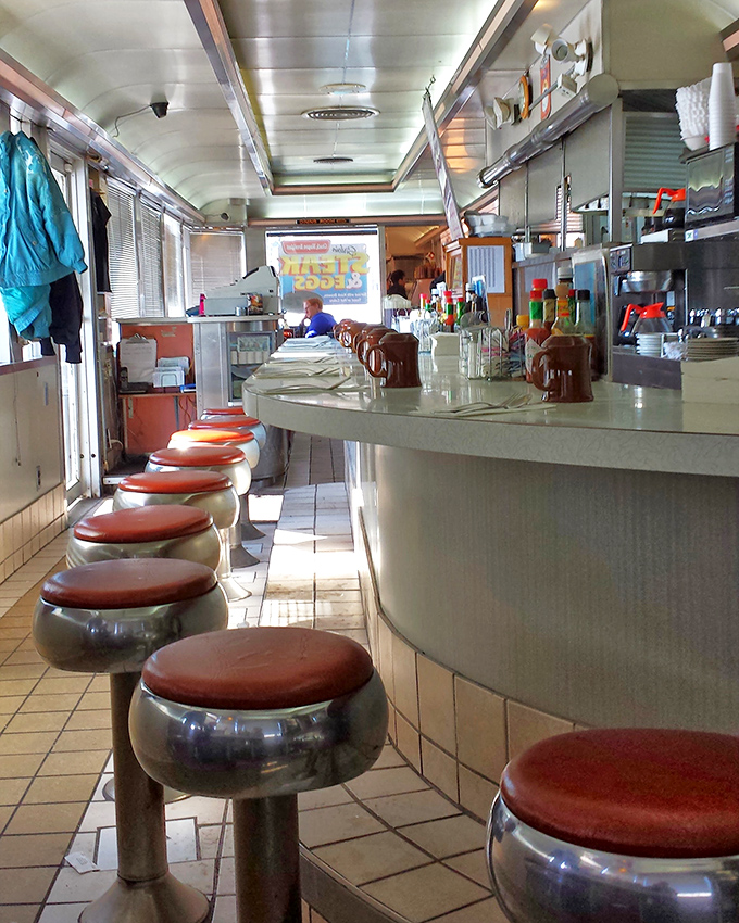 Classic diner counter stools lined up like soldiers ready for duty. That curved counter has heard more stories than most bartenders.