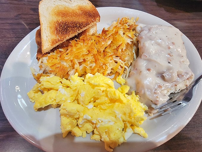 The holy trinity of breakfast comfort—golden hashbrowns, fluffy scrambled eggs, and biscuits swimming in creamy gravy. Grandma would approve, then ask for seconds.