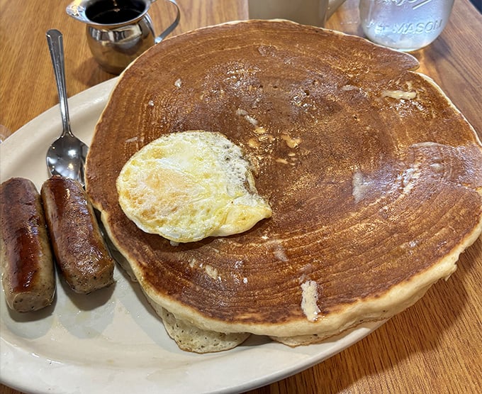 This pancake is so enormous it makes the sausage links look like breakfast appetizers—a plate that says "cancel your lunch plans."