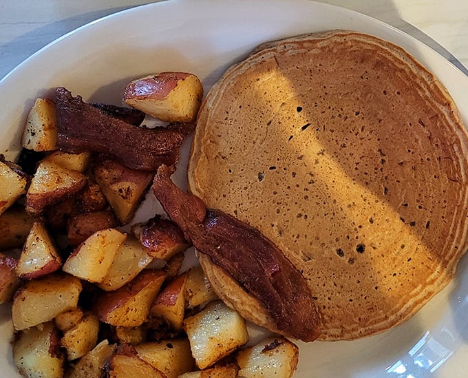 A perfectly golden pancake with a side of potatoes and bacon—the holy trinity of breakfast that's worth setting your alarm for.