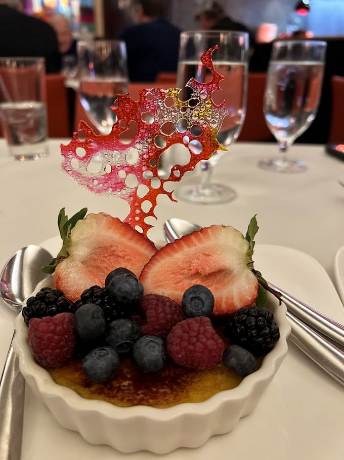 Not just crème brûlée but an entire berry festival celebrating on top. That sugar sculpture isn't showing off—okay, maybe a little.