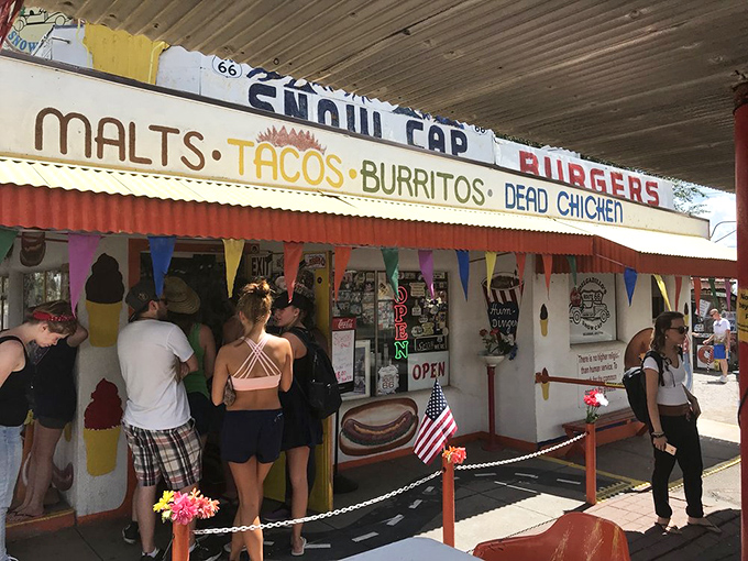 The Snow Cap's exterior welcomes hungry travelers with its "MALTS, TACOS, BURRITOS, DEAD CHICKEN" promise – a menu that's both appetizing and amusing.