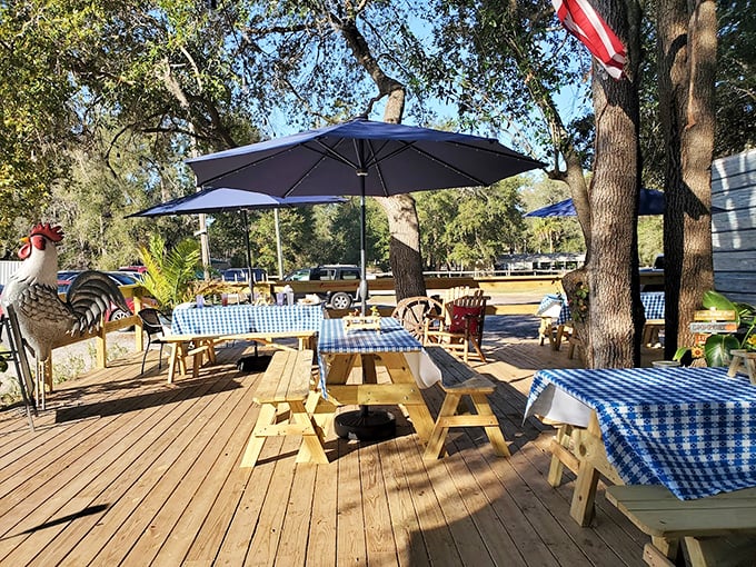 Picnic tables under umbrellas where memories are made. The rooster statue isn't just decoration—he's the unofficial greeter of this backyard paradise.