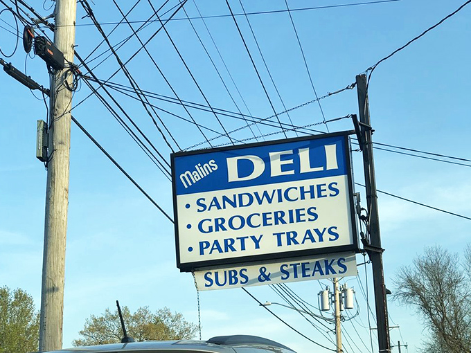 The roadside beacon that's guided hungry travelers for generations – Malin's sign promises sandwiches, groceries, and party trays with equal conviction.