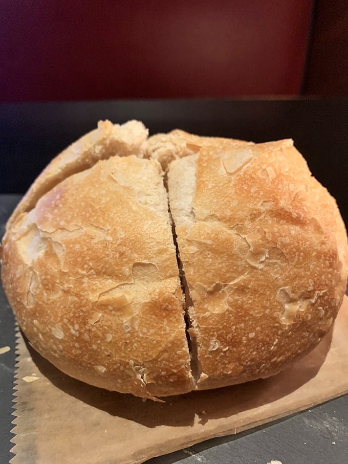 Fresh sourdough bread with that perfect crust-to-crumb ratio, served warm enough to melt butter into golden pools of happiness.