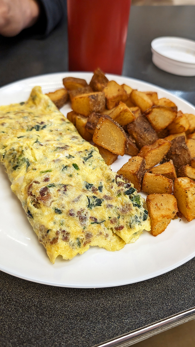 This isn't just an omelet—it's a vegetable-studded canvas of breakfast artistry paired with potatoes that achieved the perfect crisp-tender balance.