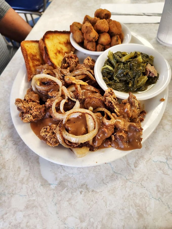 Chicken livers achieve crispy perfection alongside vibrant collard greens and golden-fried okra—a plate that tells Mississippi's culinary story in one glance.