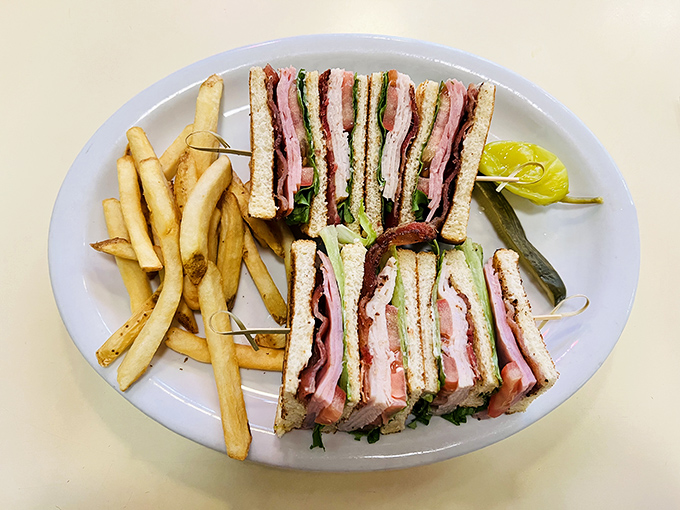 The club sandwich stands tall and proud, layers stacked with military precision—a skyscraper of flavor requiring strategic demolition techniques.
