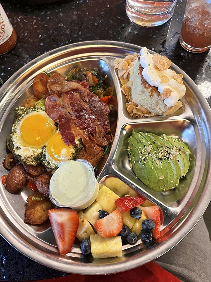 A breakfast that refuses to be boring—eggs, bacon, roasted vegetables, and sides arranged like a delicious solar system on a metal plate.