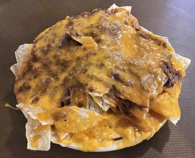 Nachos that require a strategy to eat—each chip a potential vehicle for maximum cheese-to-chili ratio perfection.