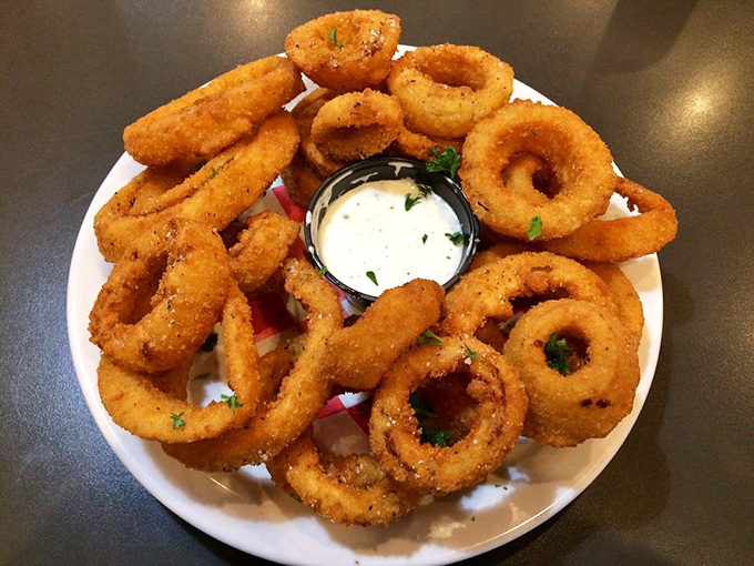 Golden onion rings stacked like delicious jewelry, with ranch dressing playing the role of the perfect diamond centerpiece.