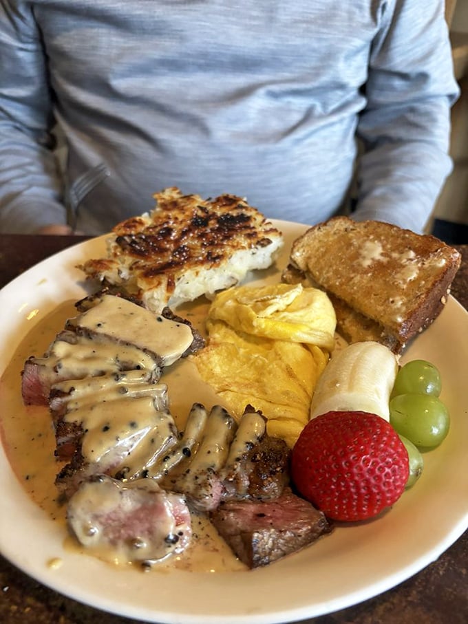 Steak and eggs elevated to art form—tender meat draped in sauce, scrambled eggs, and hash browns creating a plate of pure satisfaction.