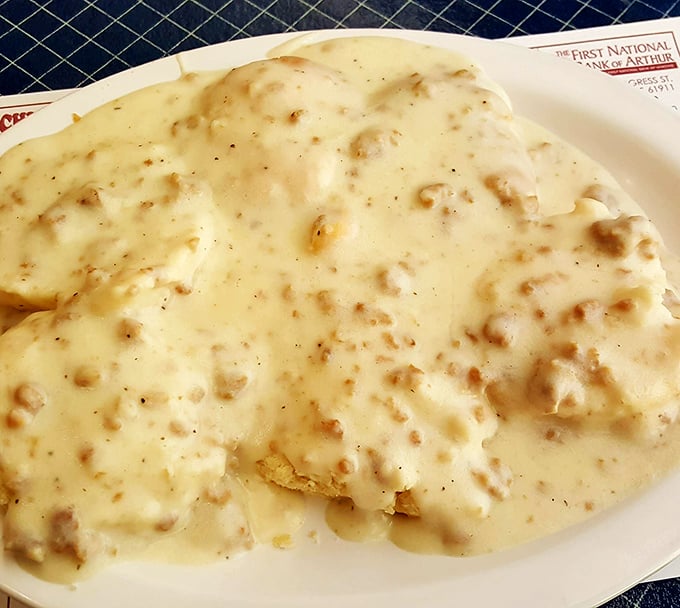 Biscuits and gravy performing their timeless duet—the fluffy base nearly obscured by a cream-colored cascade of peppery comfort.