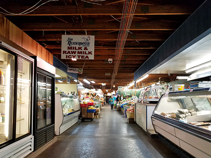 Market corridor cornucopia – refrigerated cases and family vendors create a gauntlet of temptation impossible to navigate without multiple purchases.
