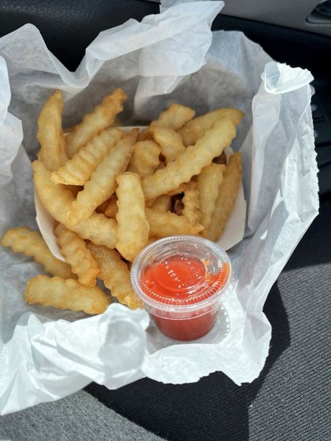 Crinkle-cut fries in paper—not served on a slate or in a miniature shopping cart, just honest potatoes done right.