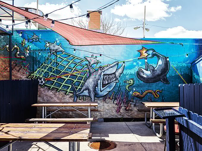 The outdoor patio features a whimsical sea-themed mural where sharks, dolphins, and fish seem to be having more fun than the diners.