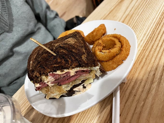 The Reuben sandwich, reimagined but respectful of tradition. Those onion rings aren't just a side—they're a golden-fried bonus track.