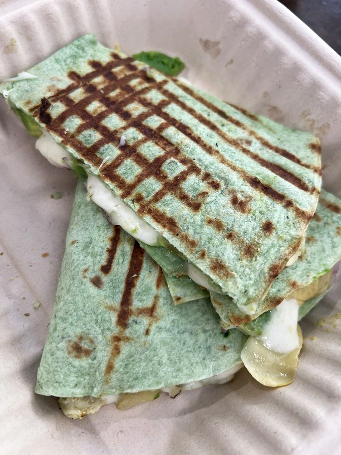 Perfectly grilled green tortilla with melted cheese peeking out like a delicious secret waiting to be discovered. Panini press perfection!