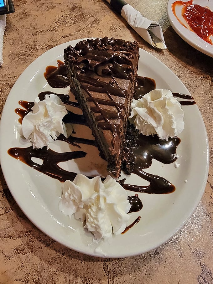 A chocolate cake so rich it probably has its own accountant. Those whipped cream dollops aren't garnish—they're necessary pauses between bites of bliss.