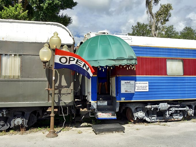 The entrance beckons with old-world charm—vintage lamppost, welcoming awning, and colorful train cars promising an experience that's definitely off the rails.